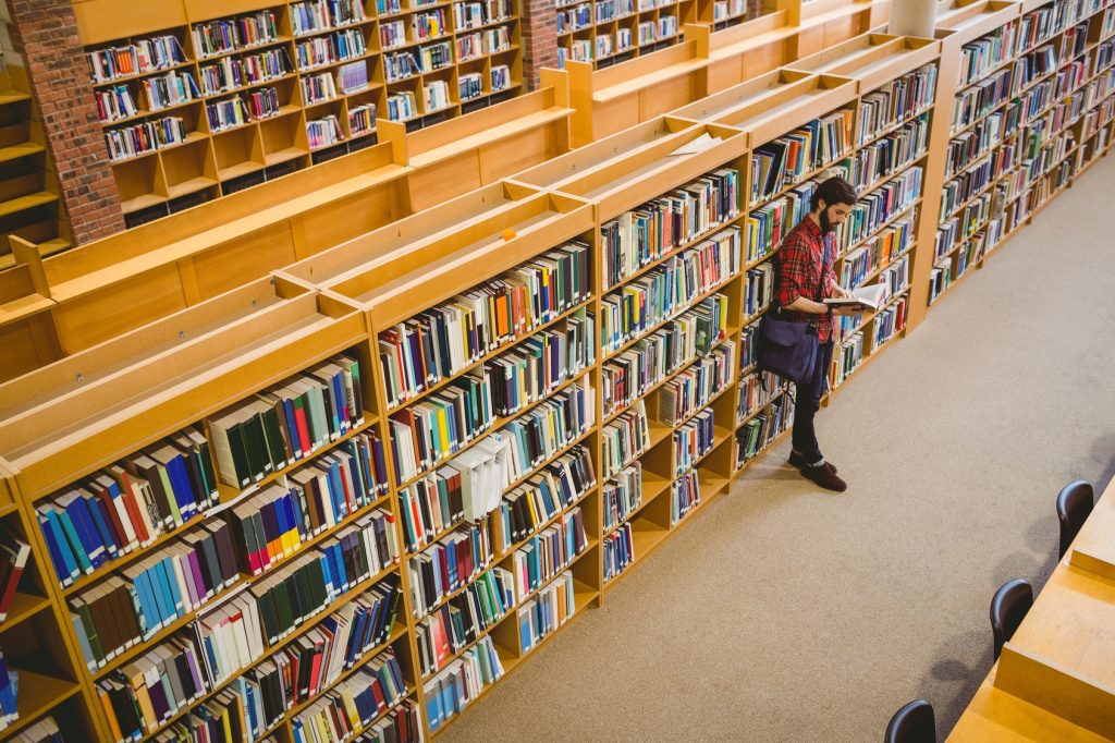 Student reading a book from shelf in library — The James G. Martin ...